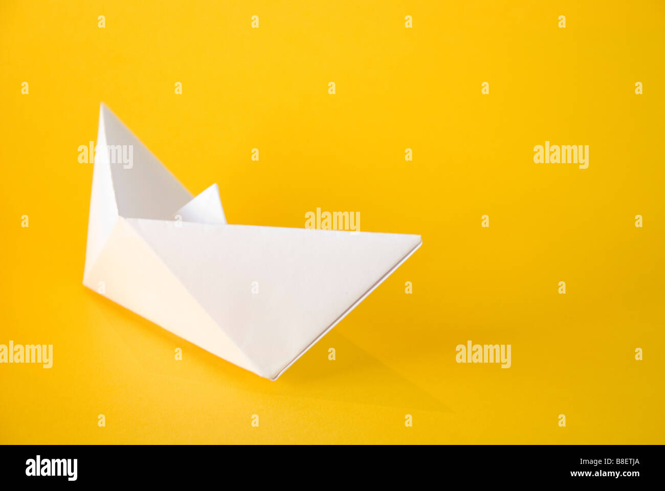 paper origami sail boat - yellow studio background Stock Photo - Alamy