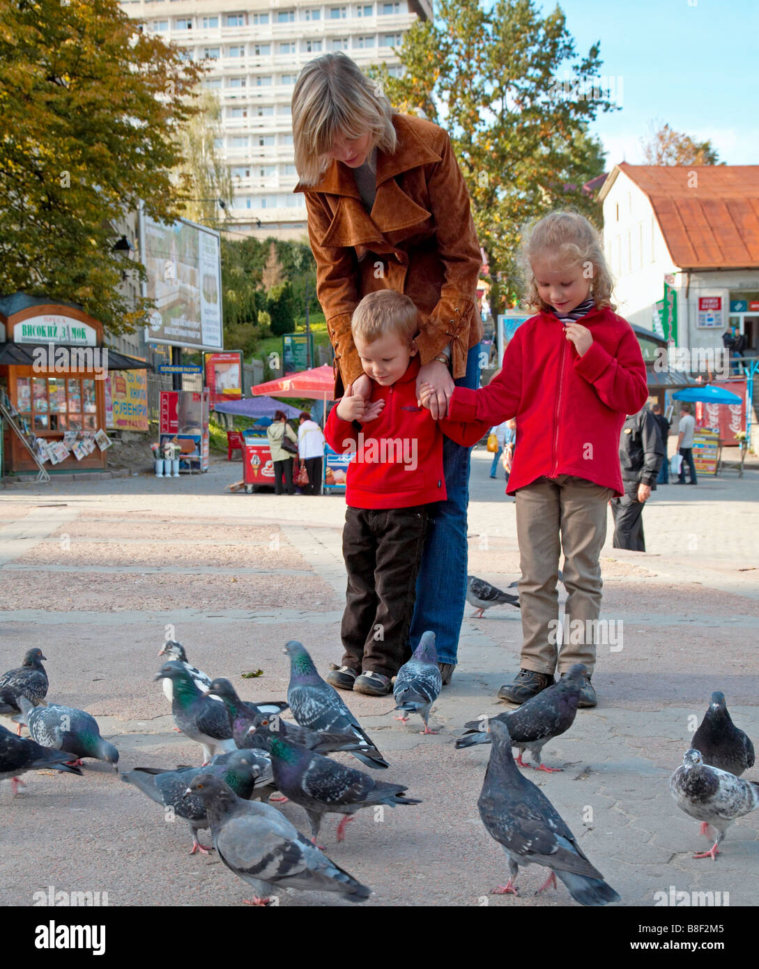 Happy family (mother with children) and wild pigeons in autumn city ...