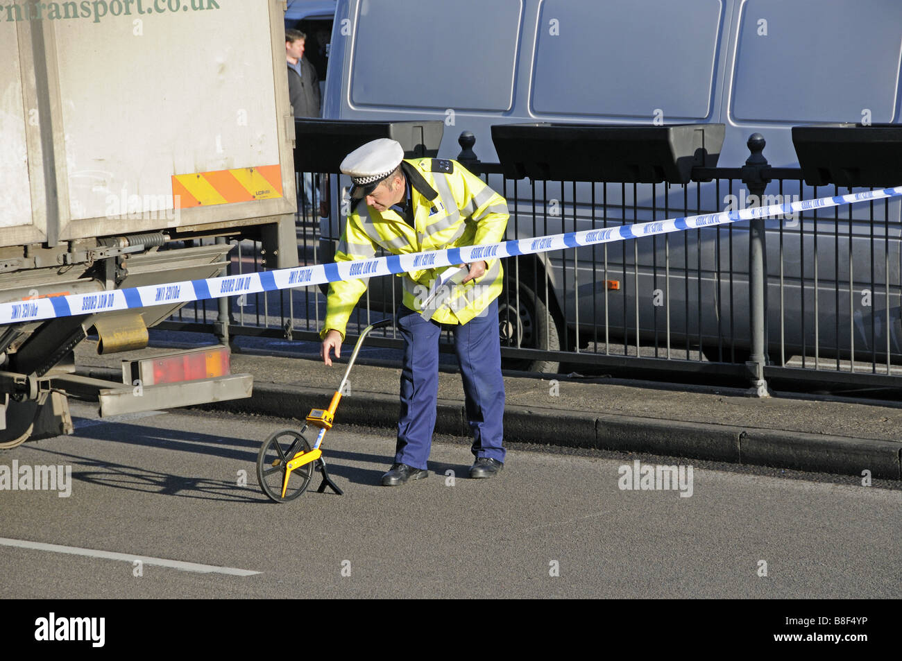 Police officer taking notes and measurements at scene of road traffic ...