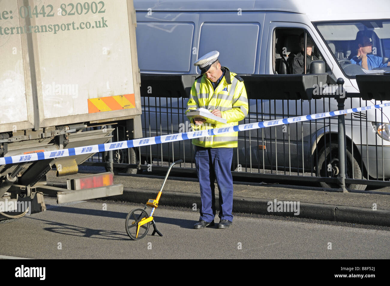 Police officer taking notes and measurements at scene of road traffic ...