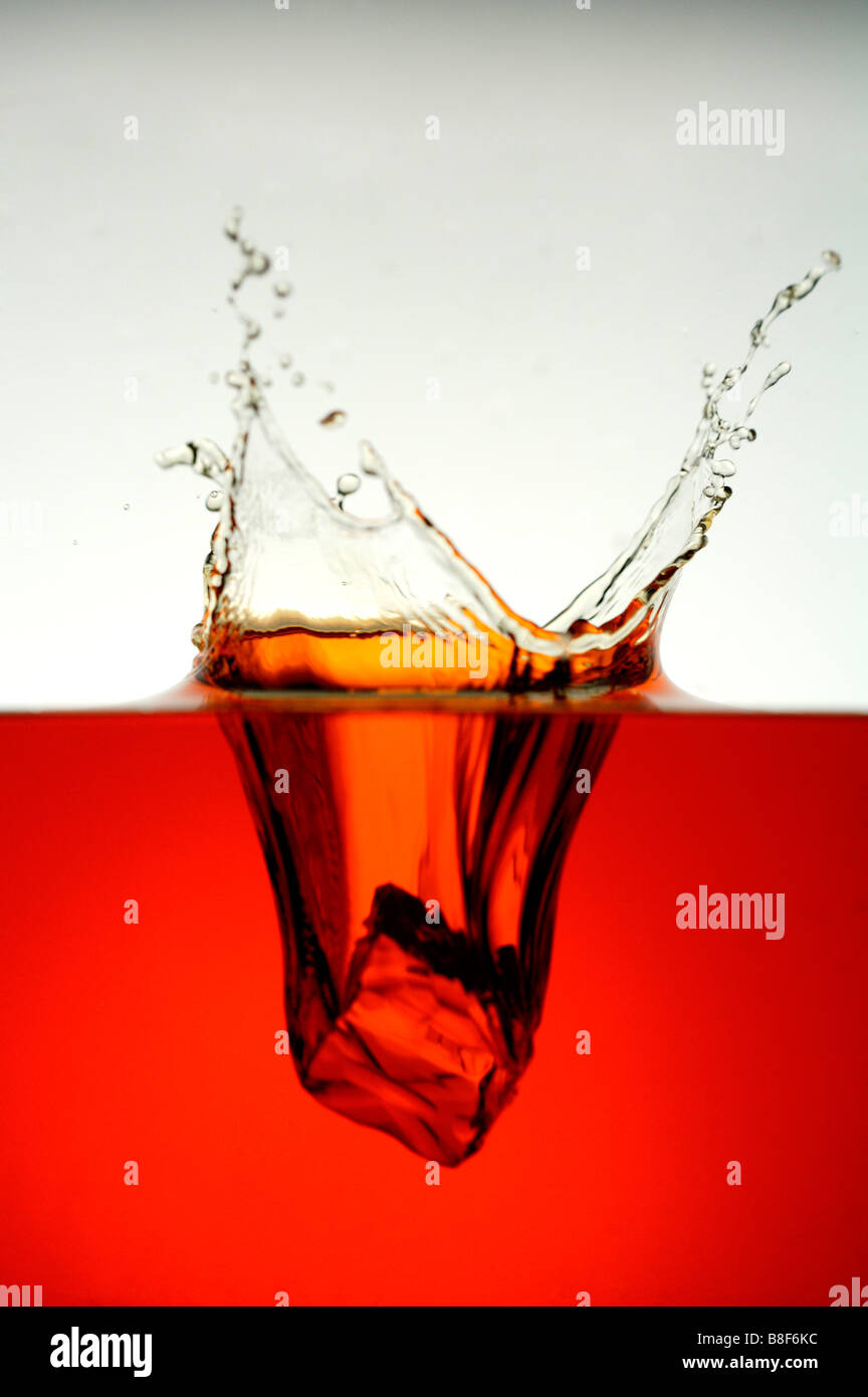Ice cube falling into the red water Stock Photo - Alamy