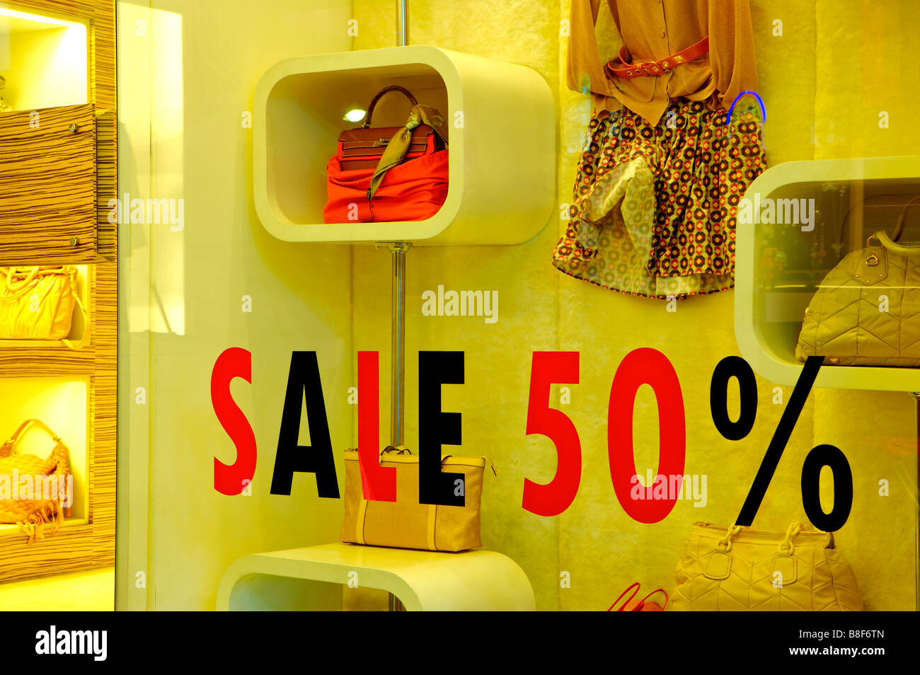 Red and black Sale sign on the window of a store with handbags and ...