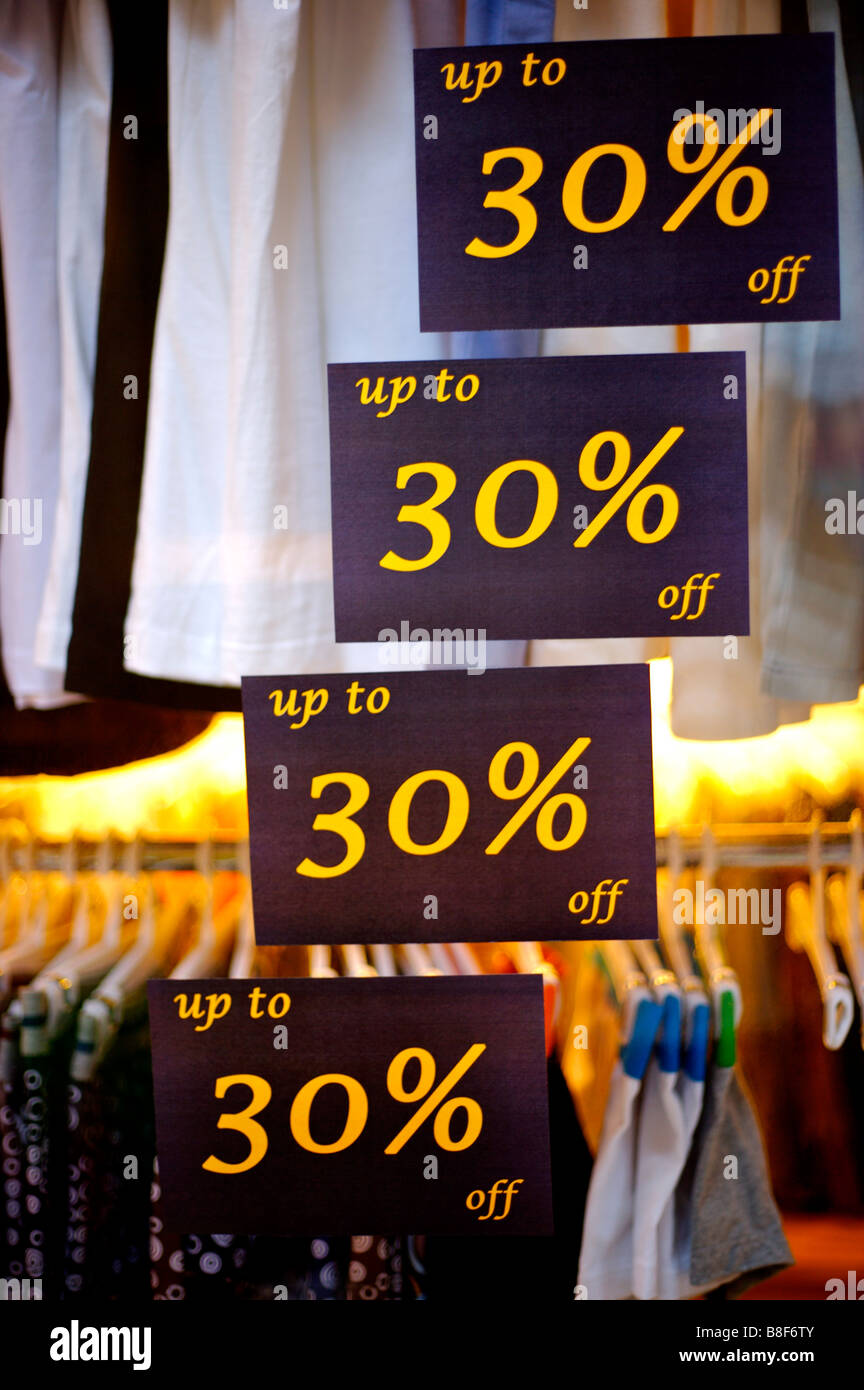 Discount signs on the window of a clothing store in front of rows of ...
