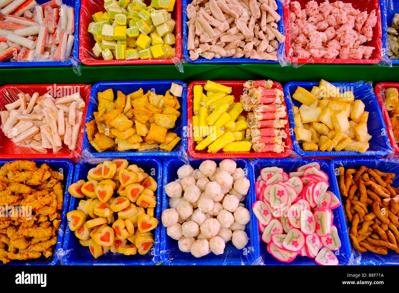 A variety of meatballs and fishballs in trays on display at a market ...