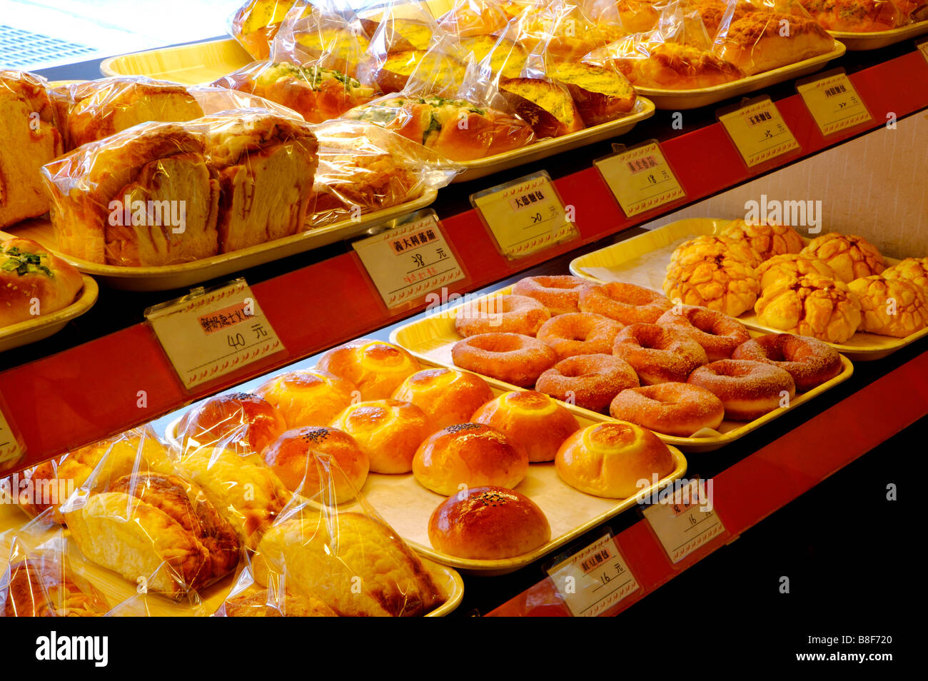 Different types of bread and buns on display in a bakery Stock Photo ...