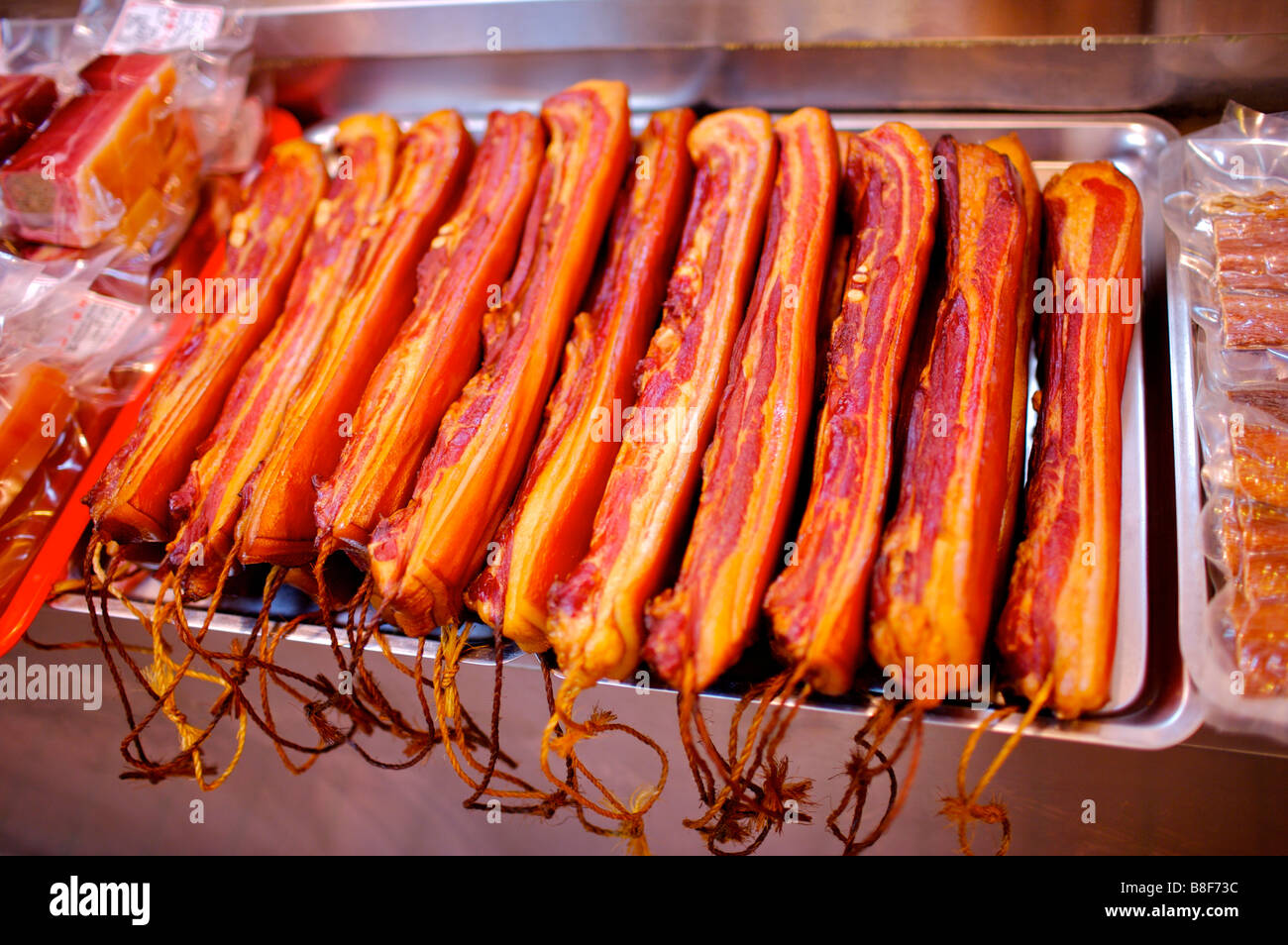 Cured pork in a row on a tray on display Stock Photo - Alamy