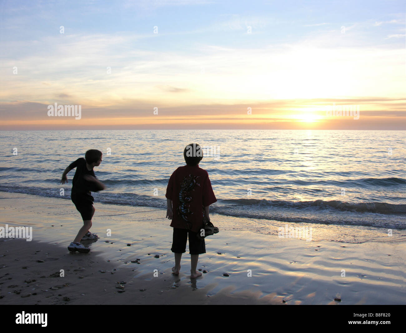 Boys playing at the beach throwing pebbles Stock Photo - Alamy