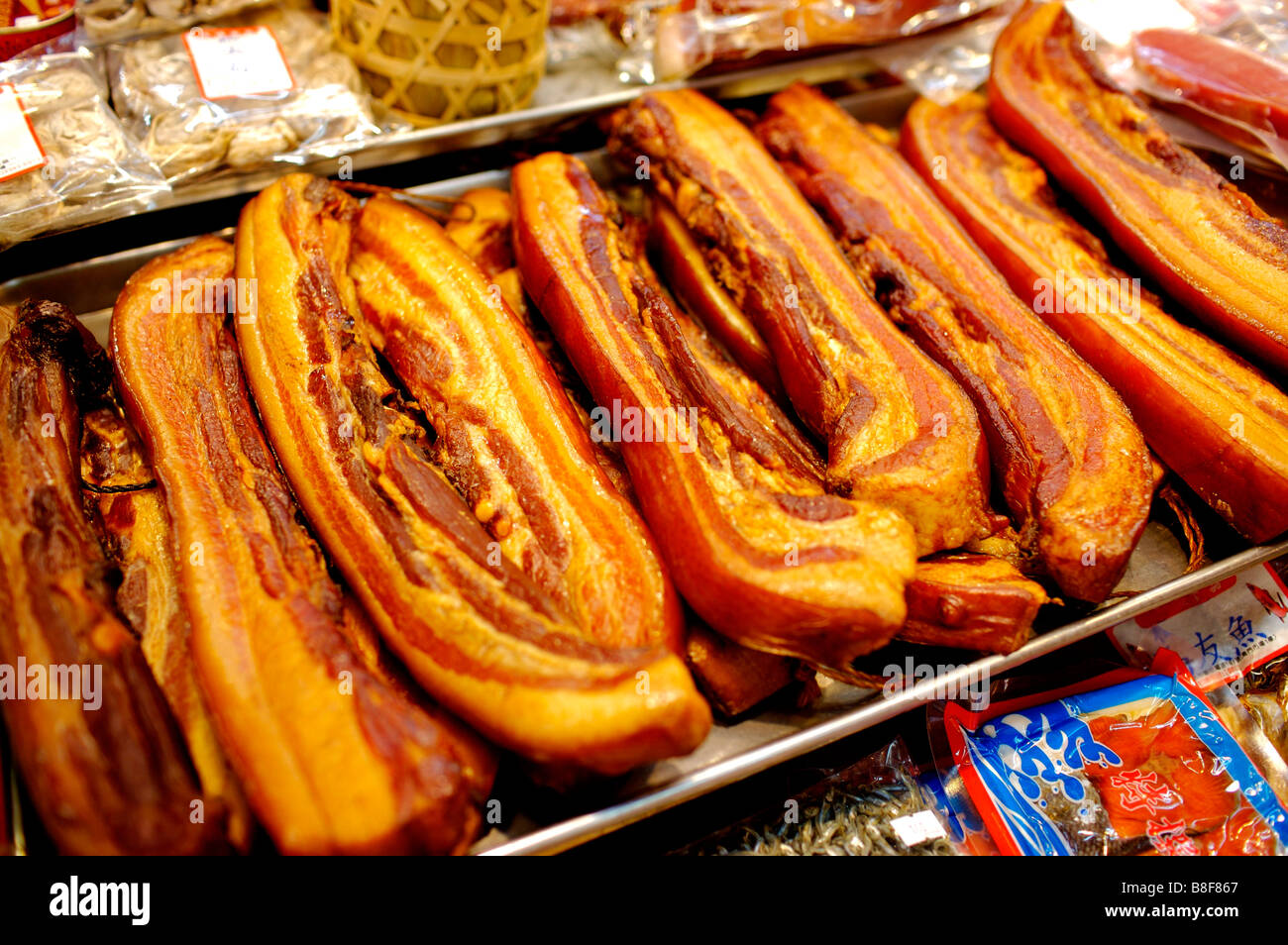 A tray of preserved pork on display next to other bags of merchandise ...