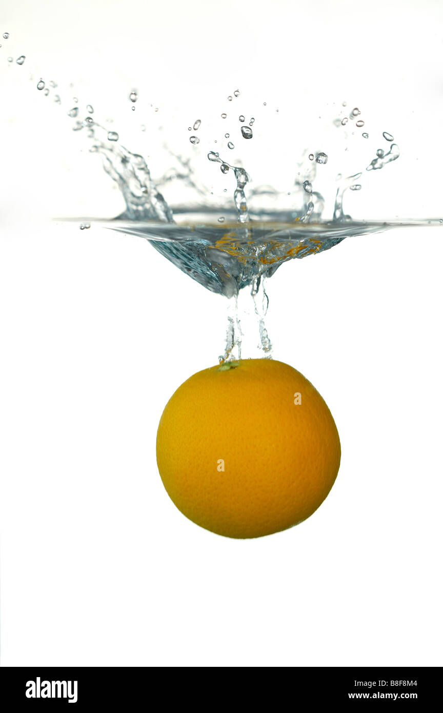 Orange falling into water splashing water upwards Stock Photo - Alamy