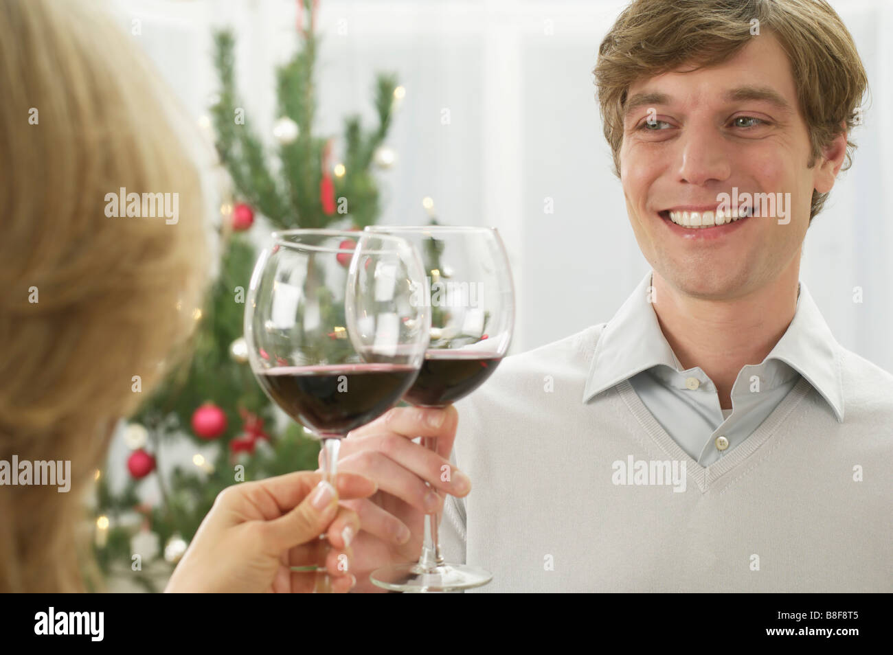 Two people chinking red wine glasses Stock Photo - Alamy