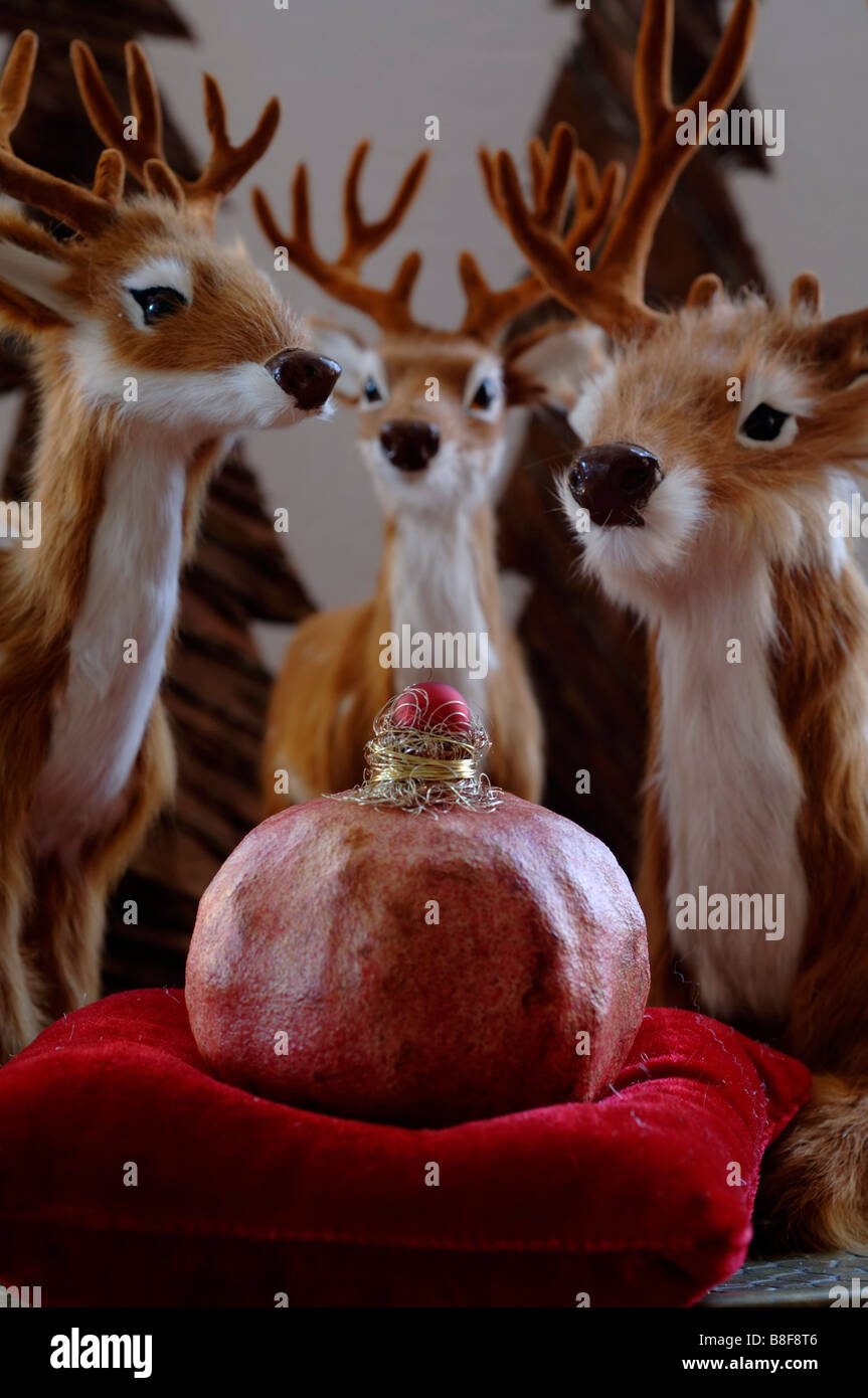 Deer (stuffed animal) standing around a red pillow with a pomegranate ...