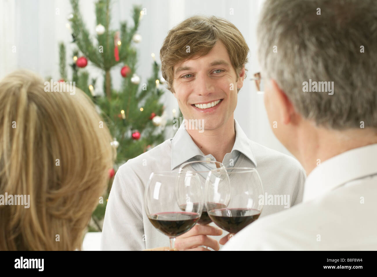 Three people chinking glasses with red wine Stock Photo - Alamy