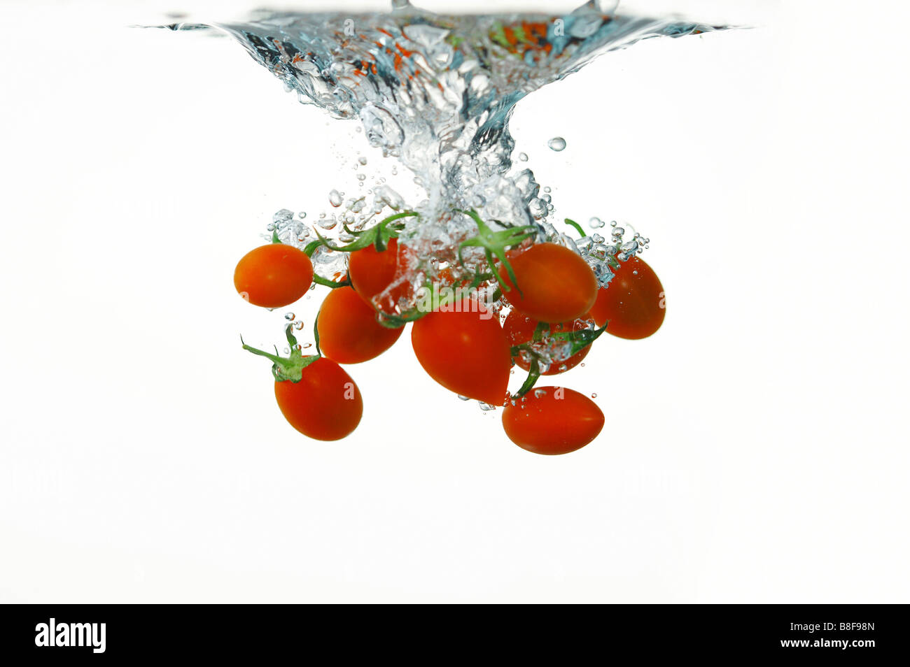 Fresh cherry tomatoes falling into water Stock Photo - Alamy