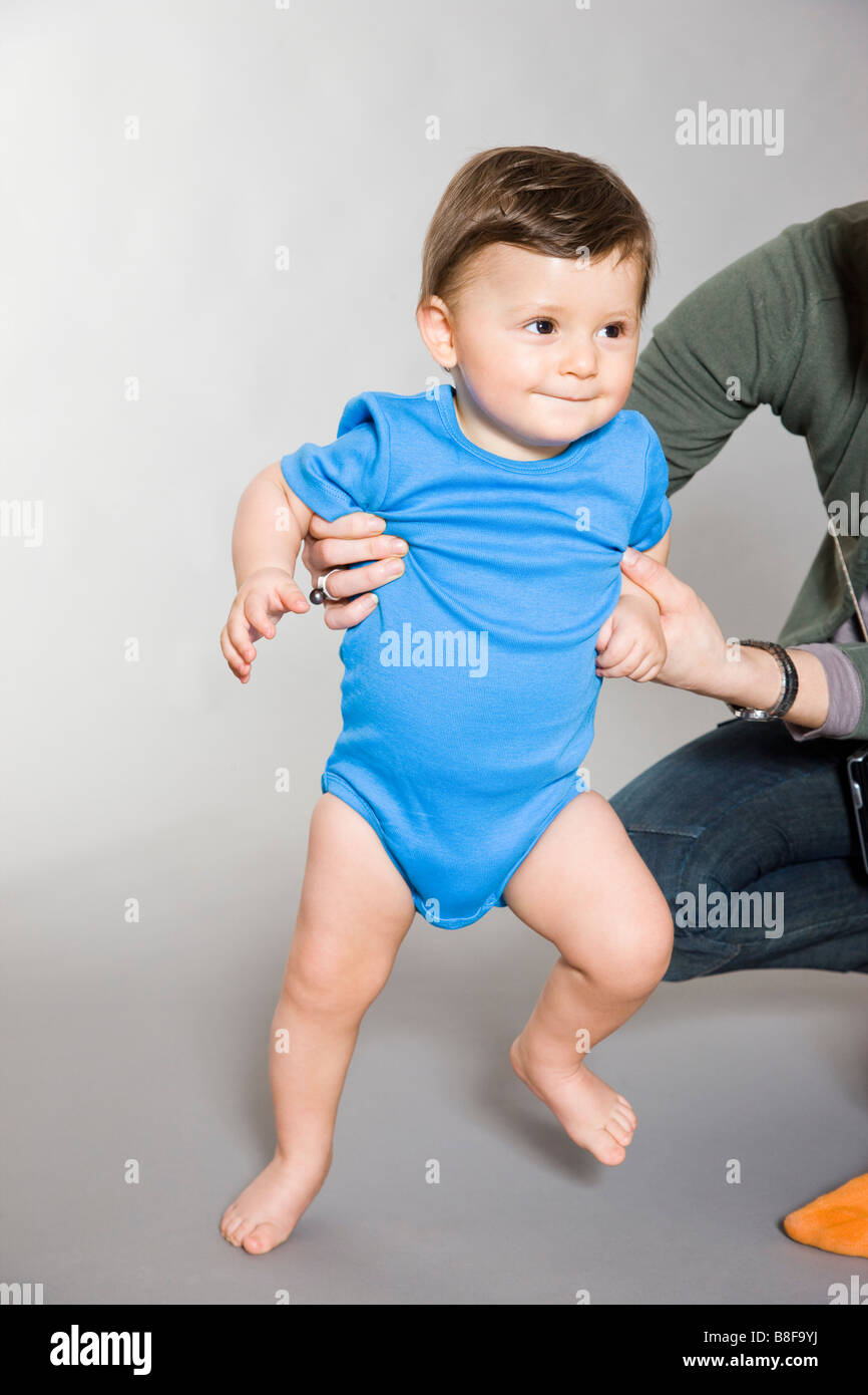 Mother teaching baby boy how to walk Stock Photo - Alamy