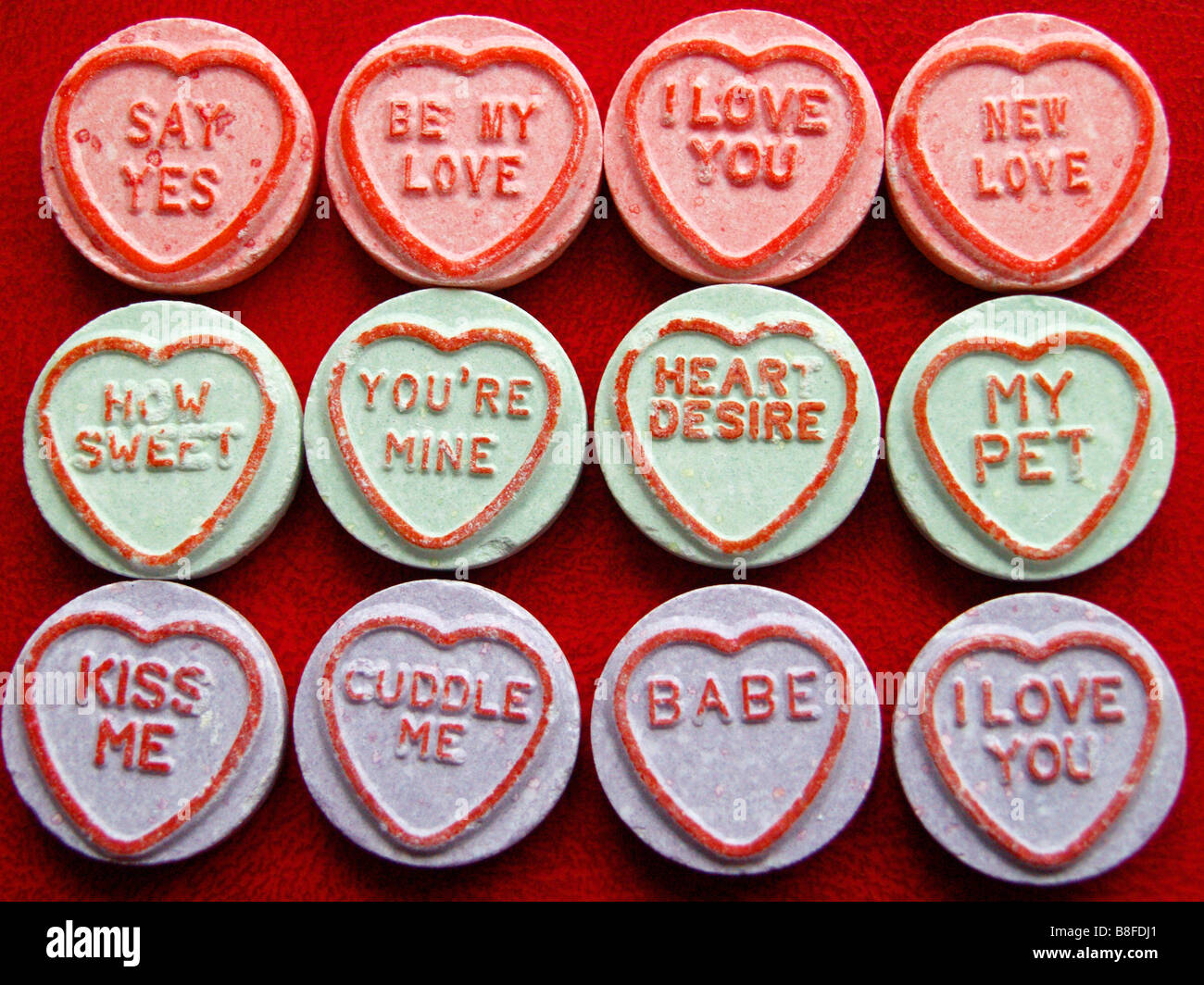Three rows of love heart sweets, against a red background Stock Photo ...