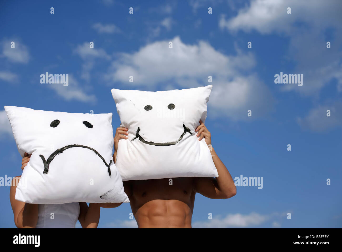 Couple covering faces by pillows with smileys Stock Photo - Alamy