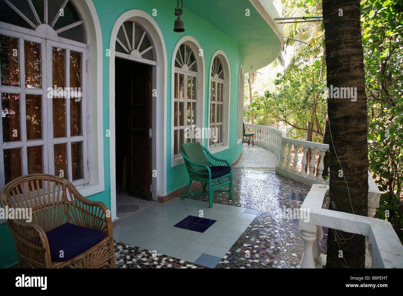 Shady veranda on old bungalow in India with arched windows and door ...