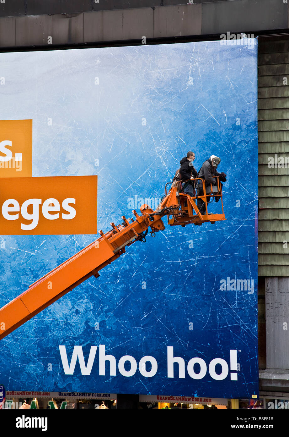 Workmen on hydraulic lift maintaining an advertising hoarding in New ...