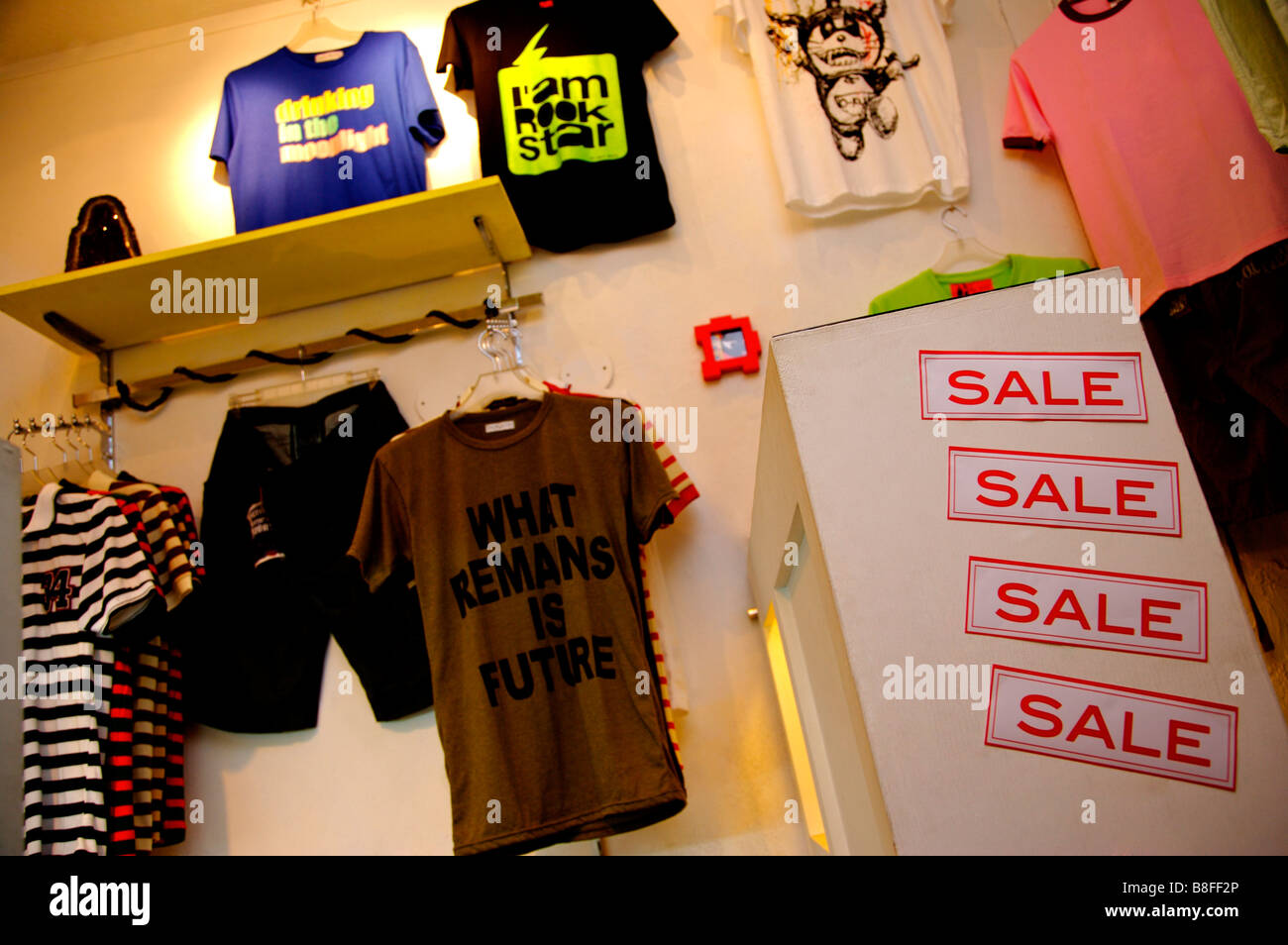 Red and white Sale signs in a clothing store with T shirts and shorts ...