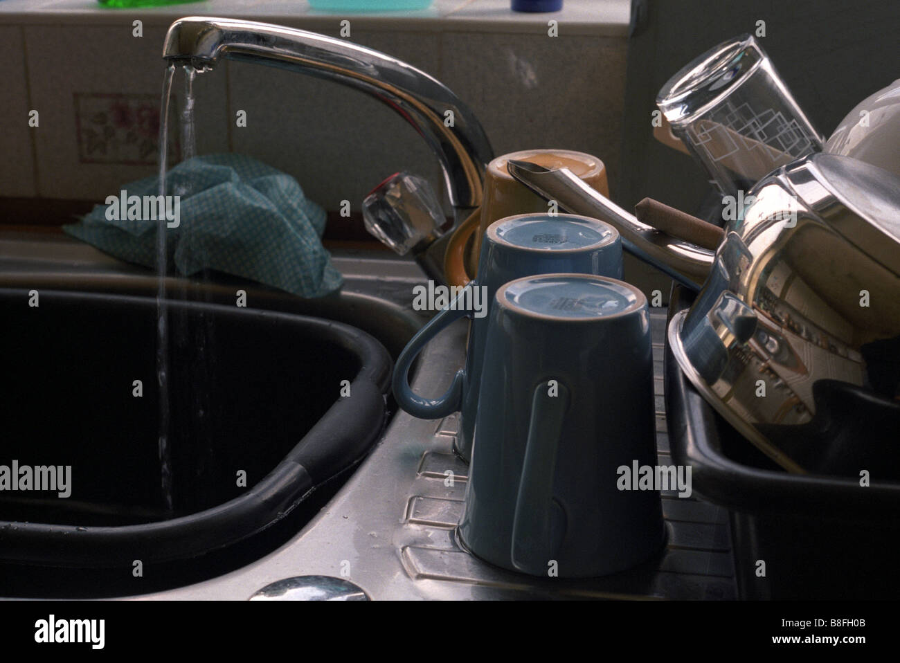 Kitchen sink with running water and dishes Stock Photo - Alamy