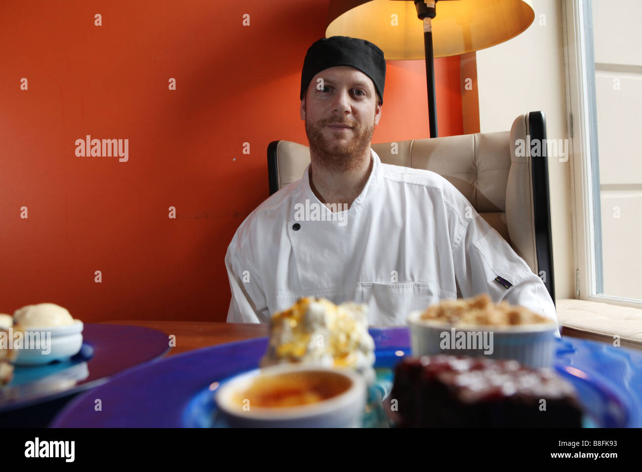 a portrait of a pastry chef sitting on a table in a restaurant with ...