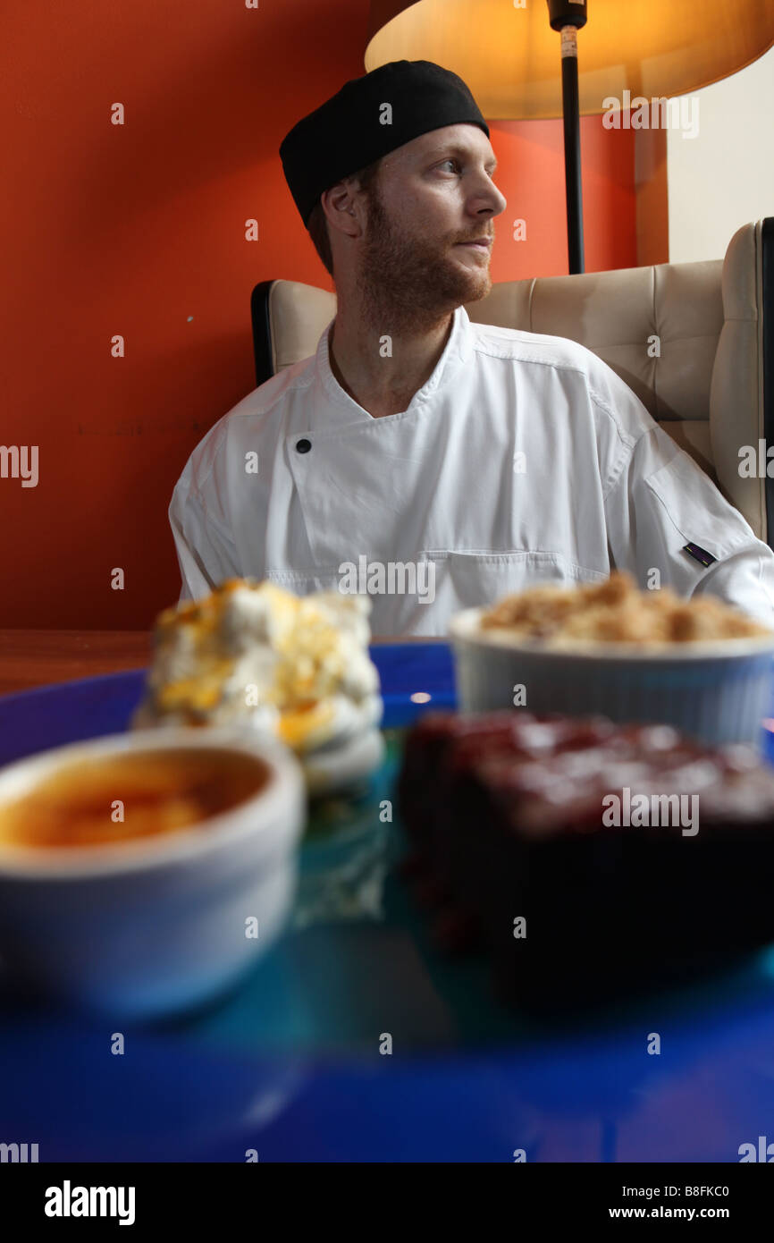 a portrait of a pastry chef sitting on a table in a restaurant with ...