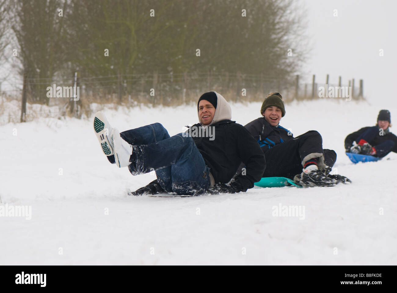 Teenagers having fun sledging in the snow on an improvised sledge Stock ...