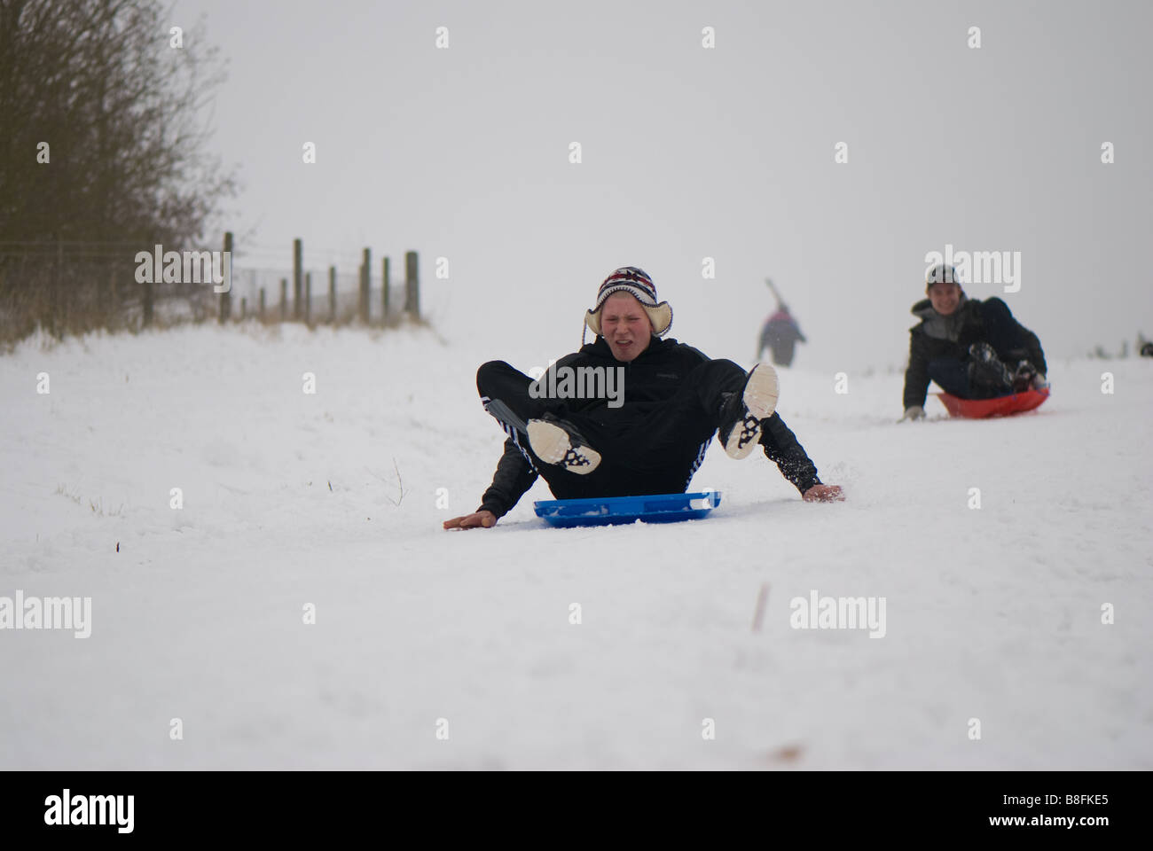 Teenagers having fun sledging in the snow on an improvised sledge Stock ...