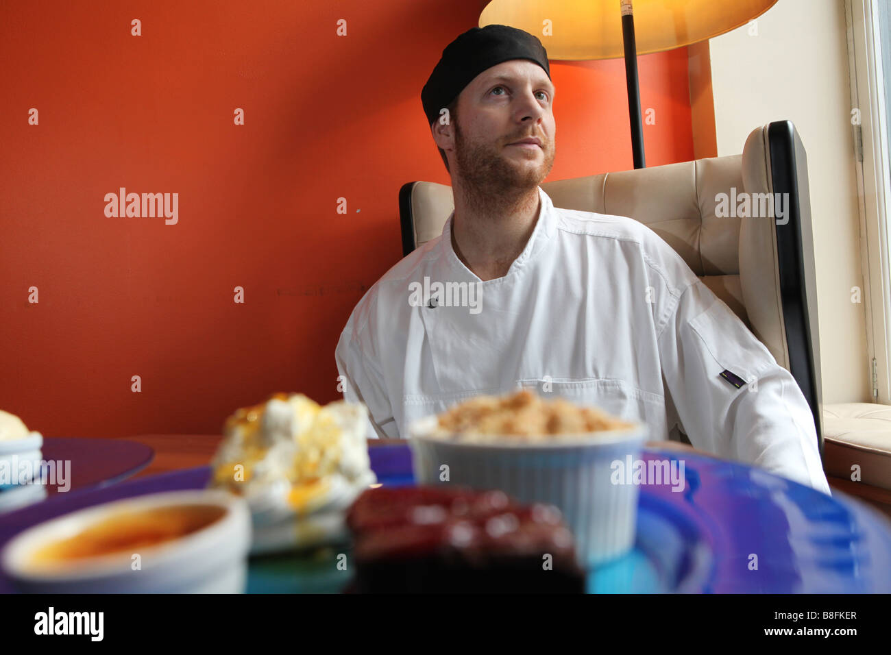 a portrait of a pastry chef sitting on a table in a restaurant with ...