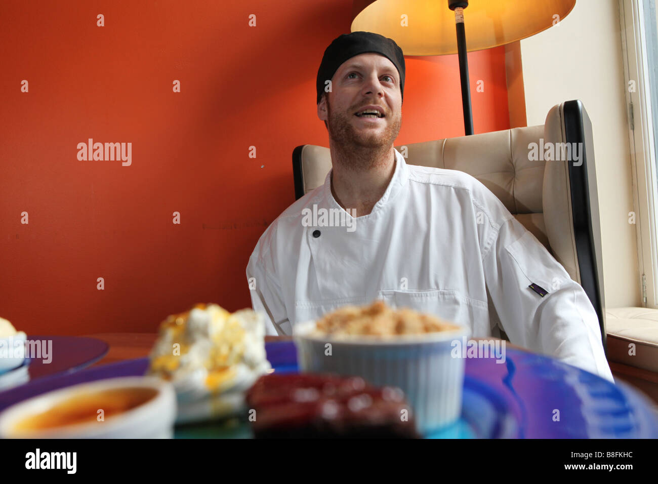 a portrait of a pastry chef sitting on a table in a restaurant with ...