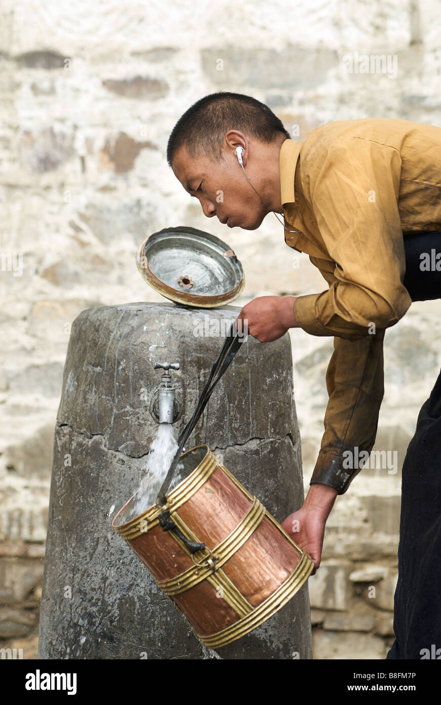 Tibetan man undertaking chores at monastery, Gyantse, Tibet. Washing ...