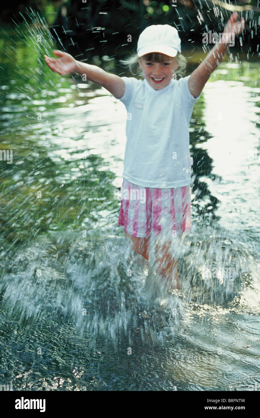 Girl splashing water playing in stream childhood happy mischief ...