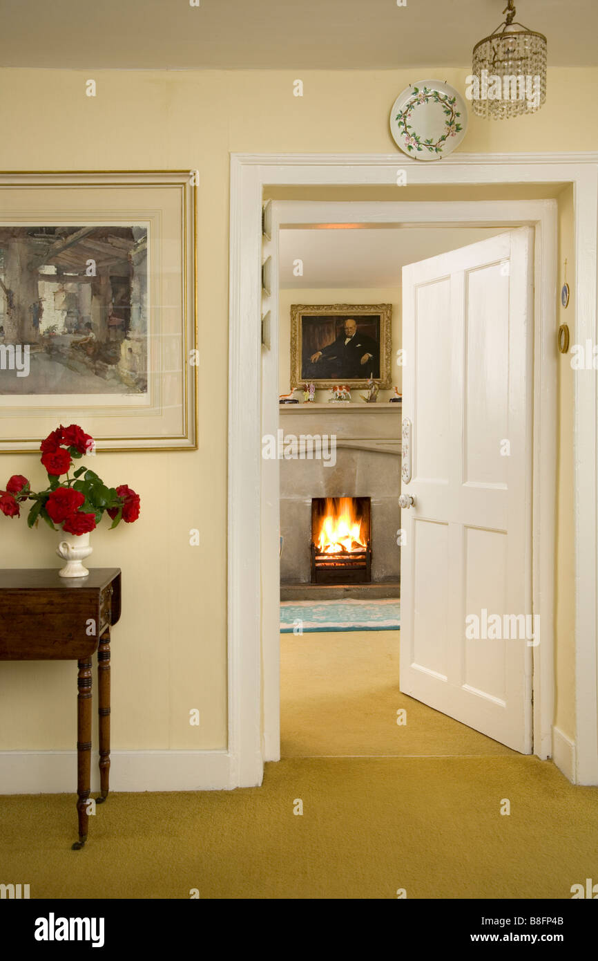 UK. A view through an open door to a cosy roaring fire in a traditional ...