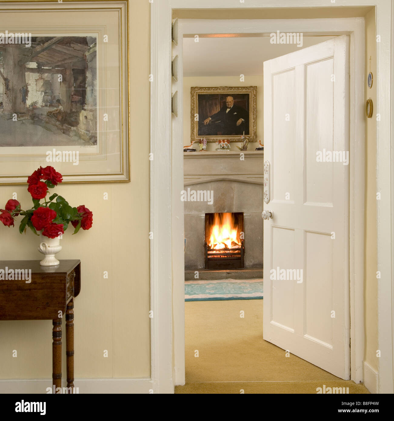 UK. A view through an open door to a cosy roaring fire in a traditional ...