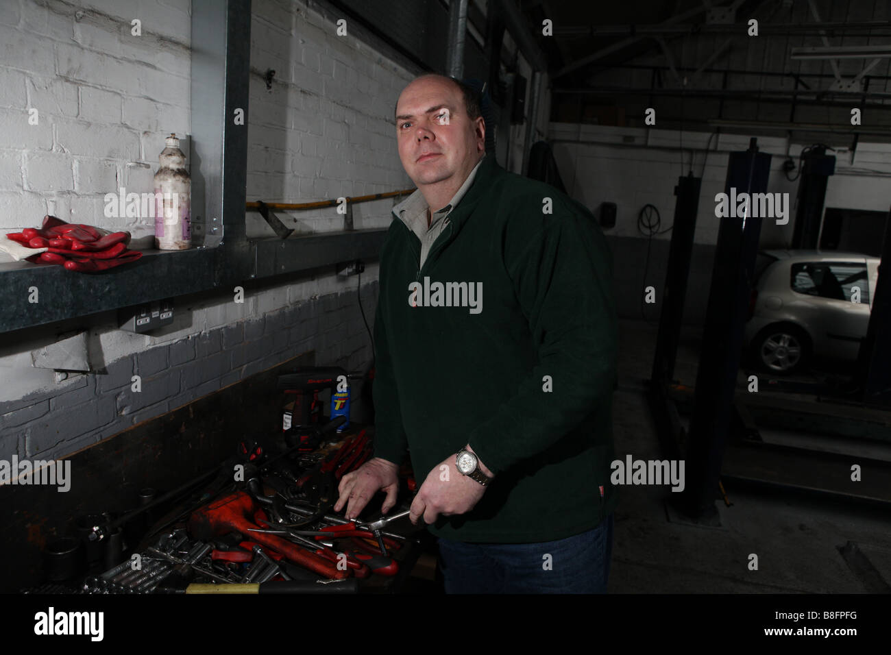 a portrait of a male mechanic at work on a car in his garage or ...