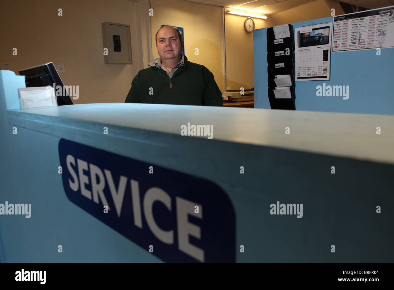 a portrait of a mechanic in the reception of a car servicing garage. He ...