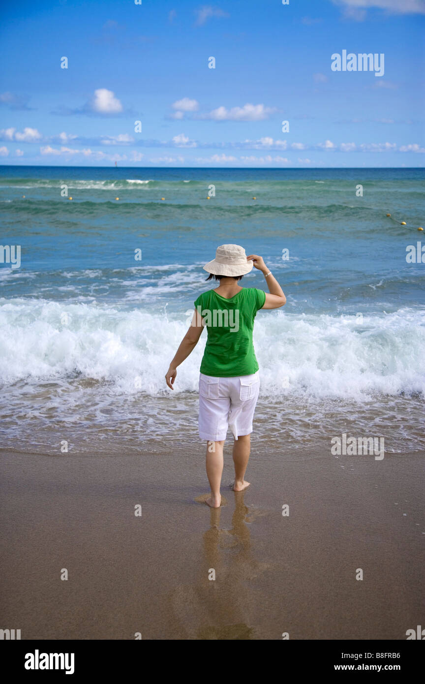A women is standing on the sand and walking towards the beach Stock ...