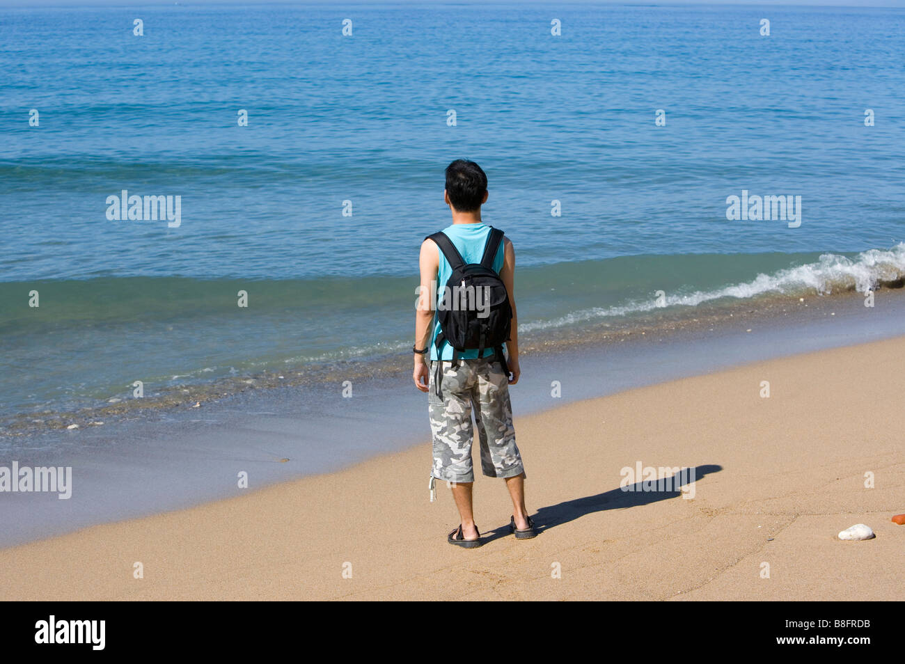 A backpacker standing at beach looking at the sea Stock Photo - Alamy