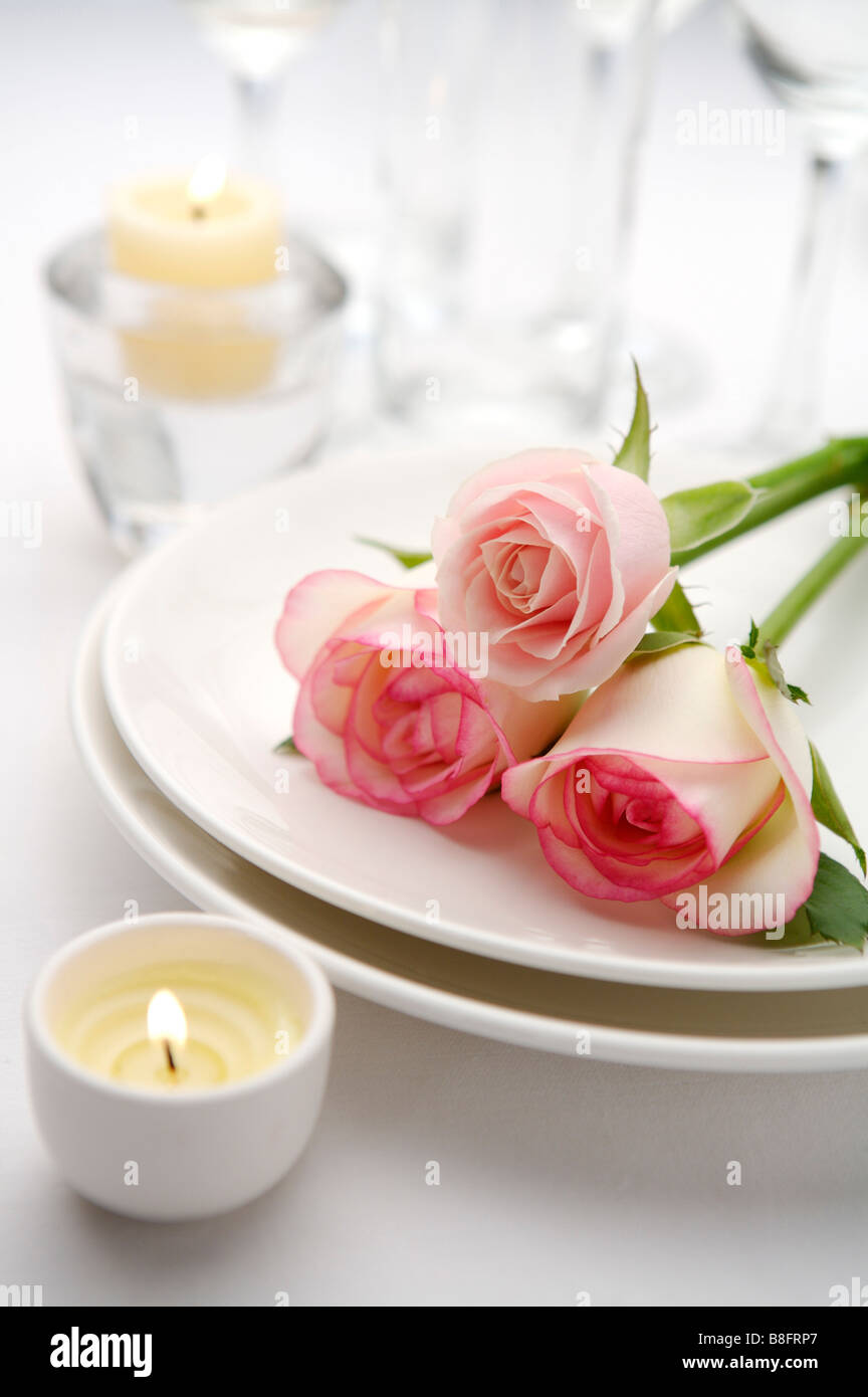 Three pink roses on the plate and lit candles Stock Photo - Alamy