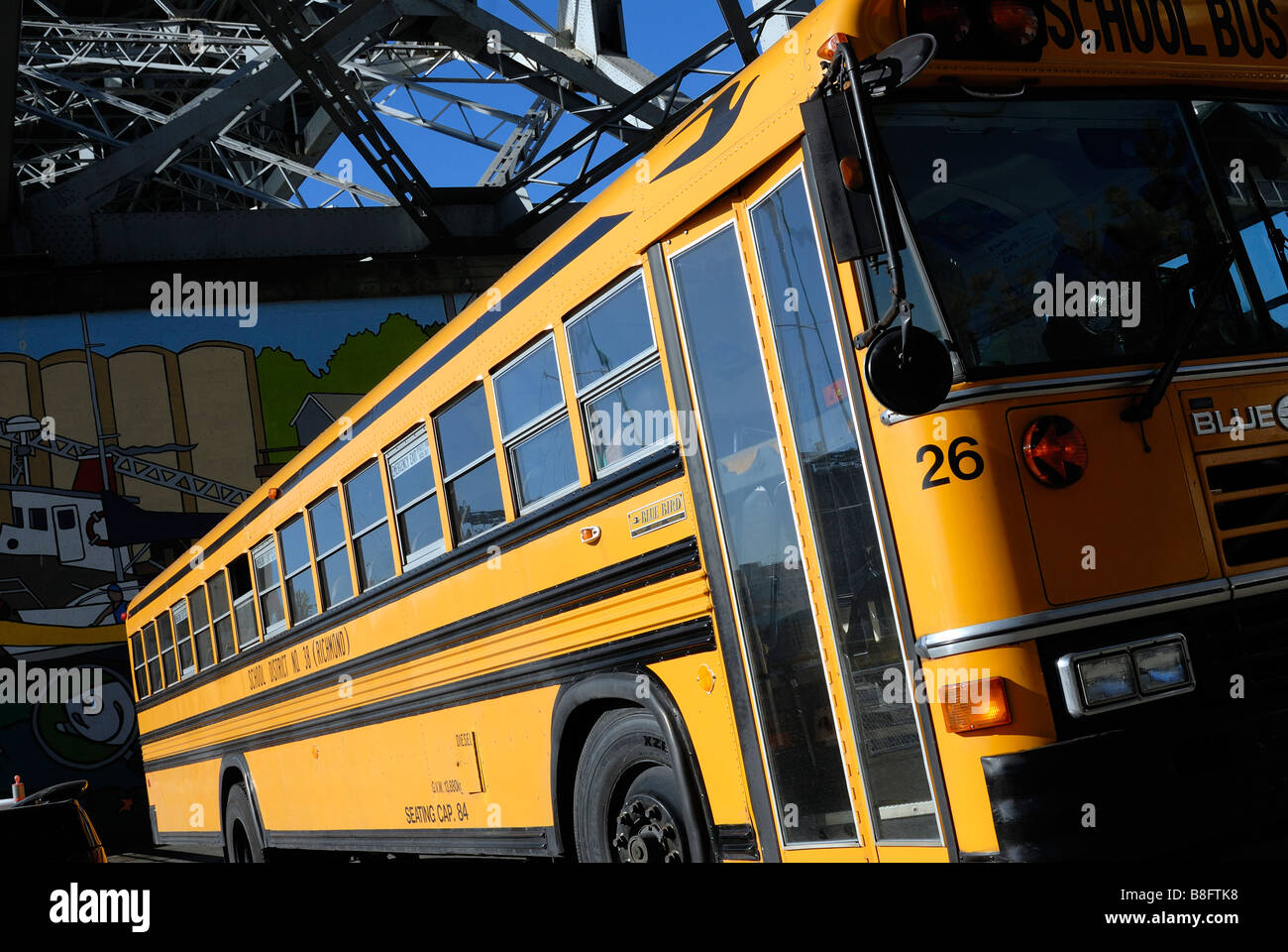 a yellow american school bus park under a steel frame bridge Stock ...