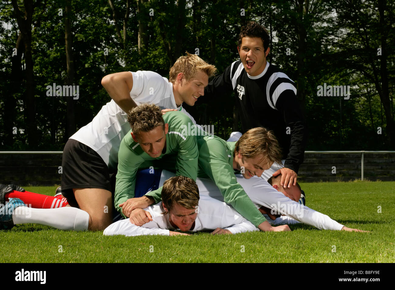 Young footballers lying onto each other and stretching out their arms ...