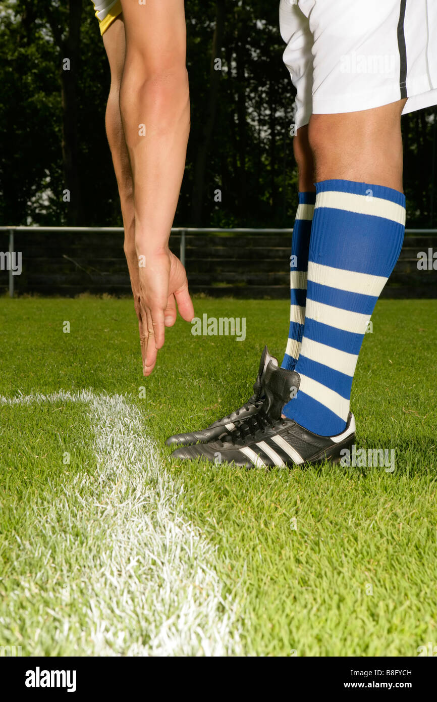 Young footballer stretching his arms down to his feet (part of ...