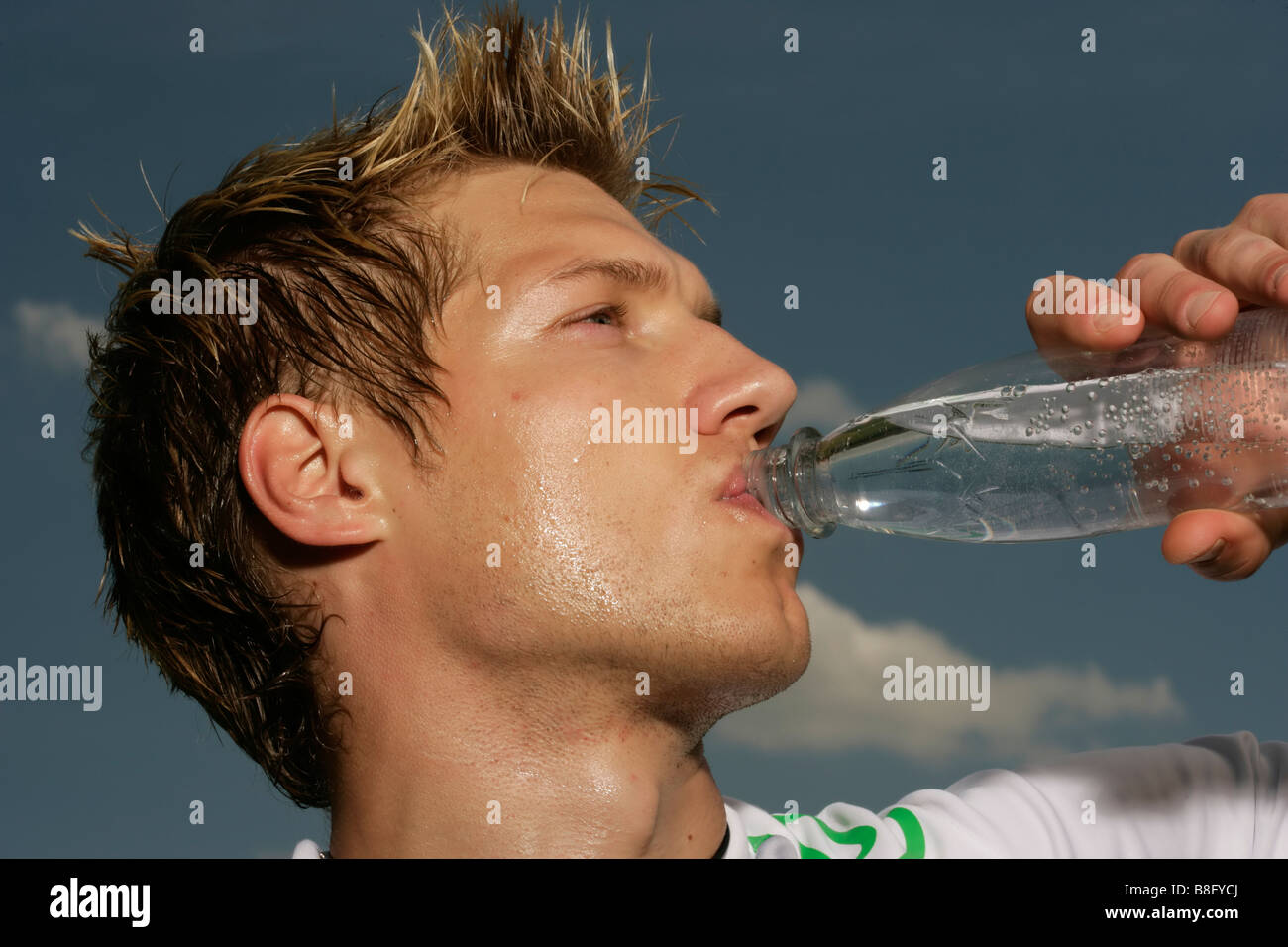 Young blond man with a sweaty face drinking from a water bottle Stock ...