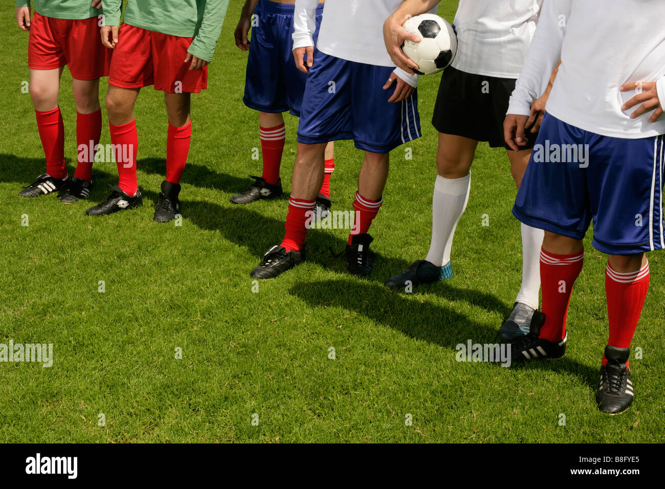 Six footballers in sports wear standing next to each other on a pitch ...
