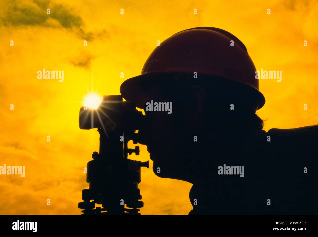 SURVEYOR IN HARD HAT WITH THEODOLITE YELLOW SKY Stock Photo - Alamy