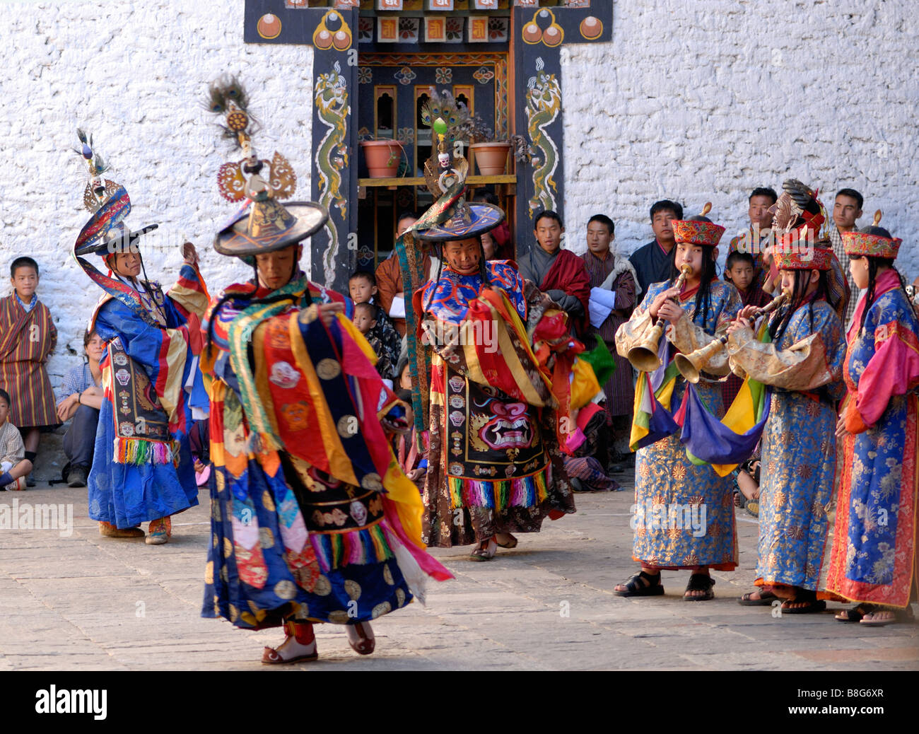 A Bhutanese audience in formal national dress watches as musicians ...