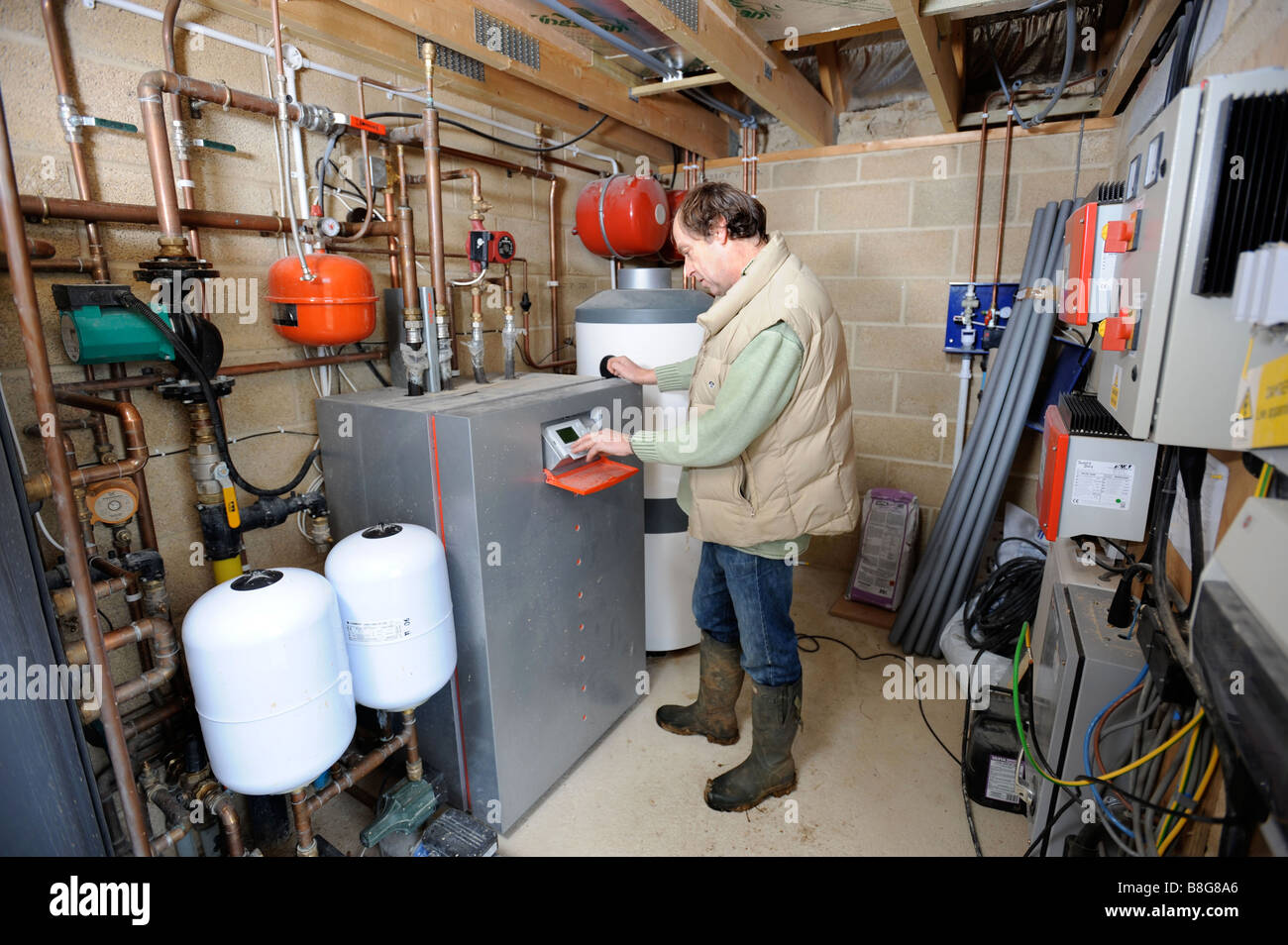 THE OWNER OF AN ENERGY EFFICIENT HOUSE ADJUSTS THE CONTROL PANEL IN THE ...
