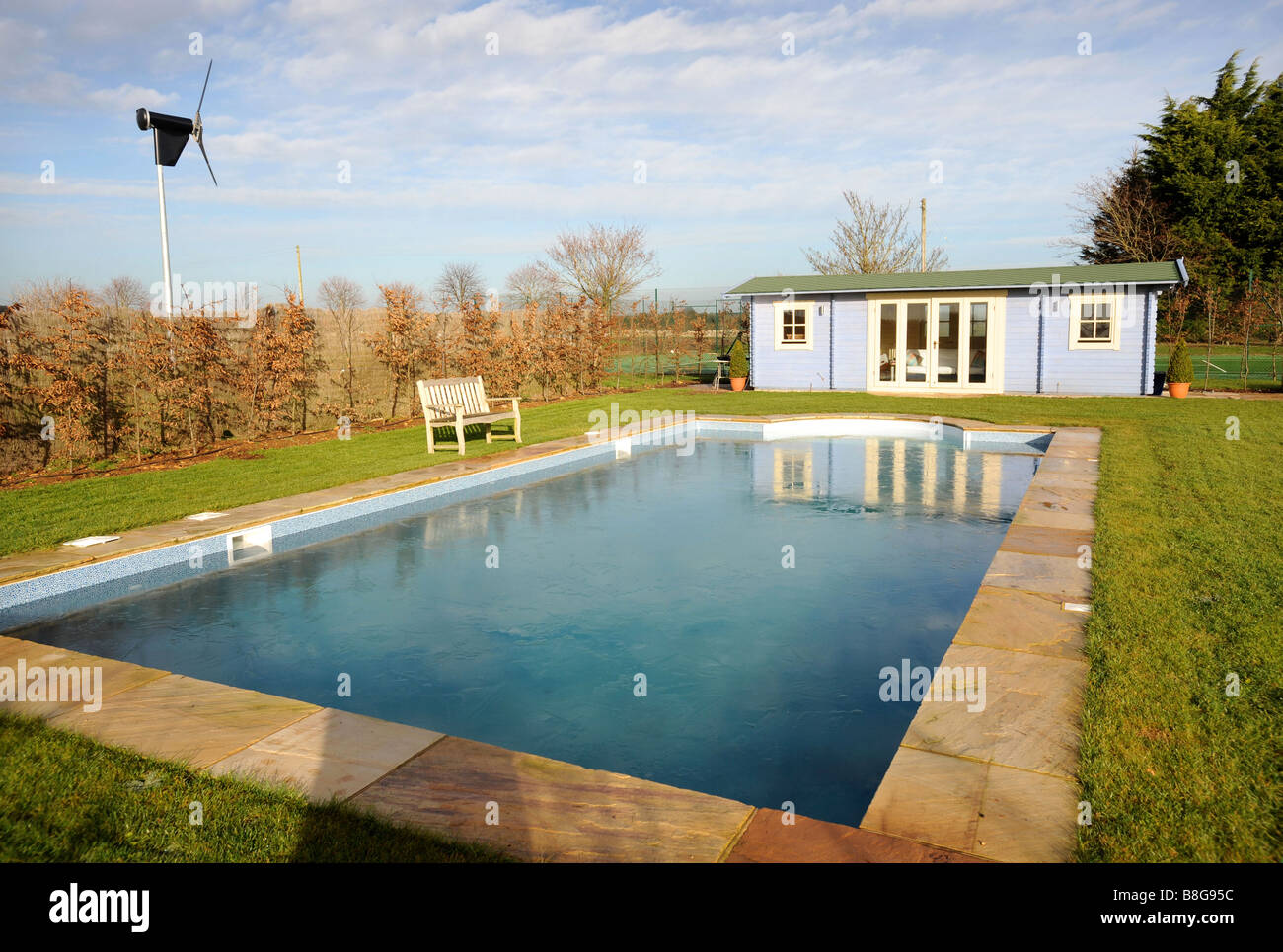 A SWIMMING POOL AT AN ENERGY EFFICIENT HOME WITH A WIND TURBINE AND ...