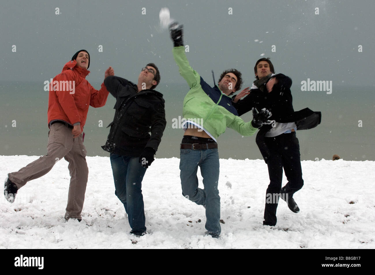 Four young men throwing snowballs Stock Photo - Alamy