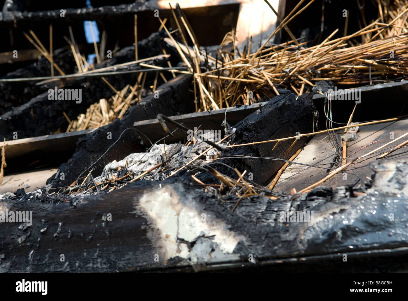 Thatched roof of cottage on fire burnt joists and thatch tie rods Stock ...